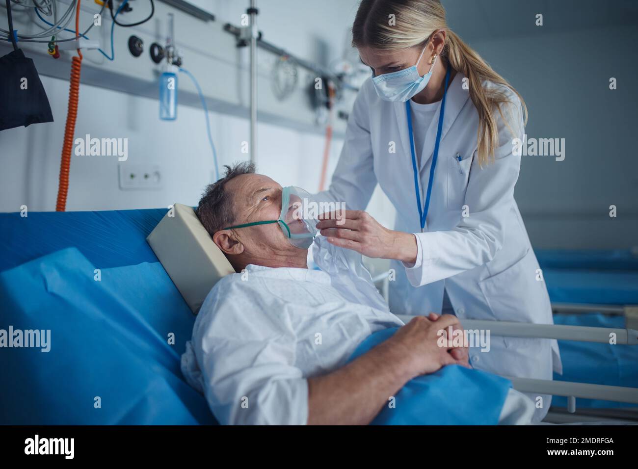 Young woman doctor putting on oxygen mask to elderly patient Stock ...