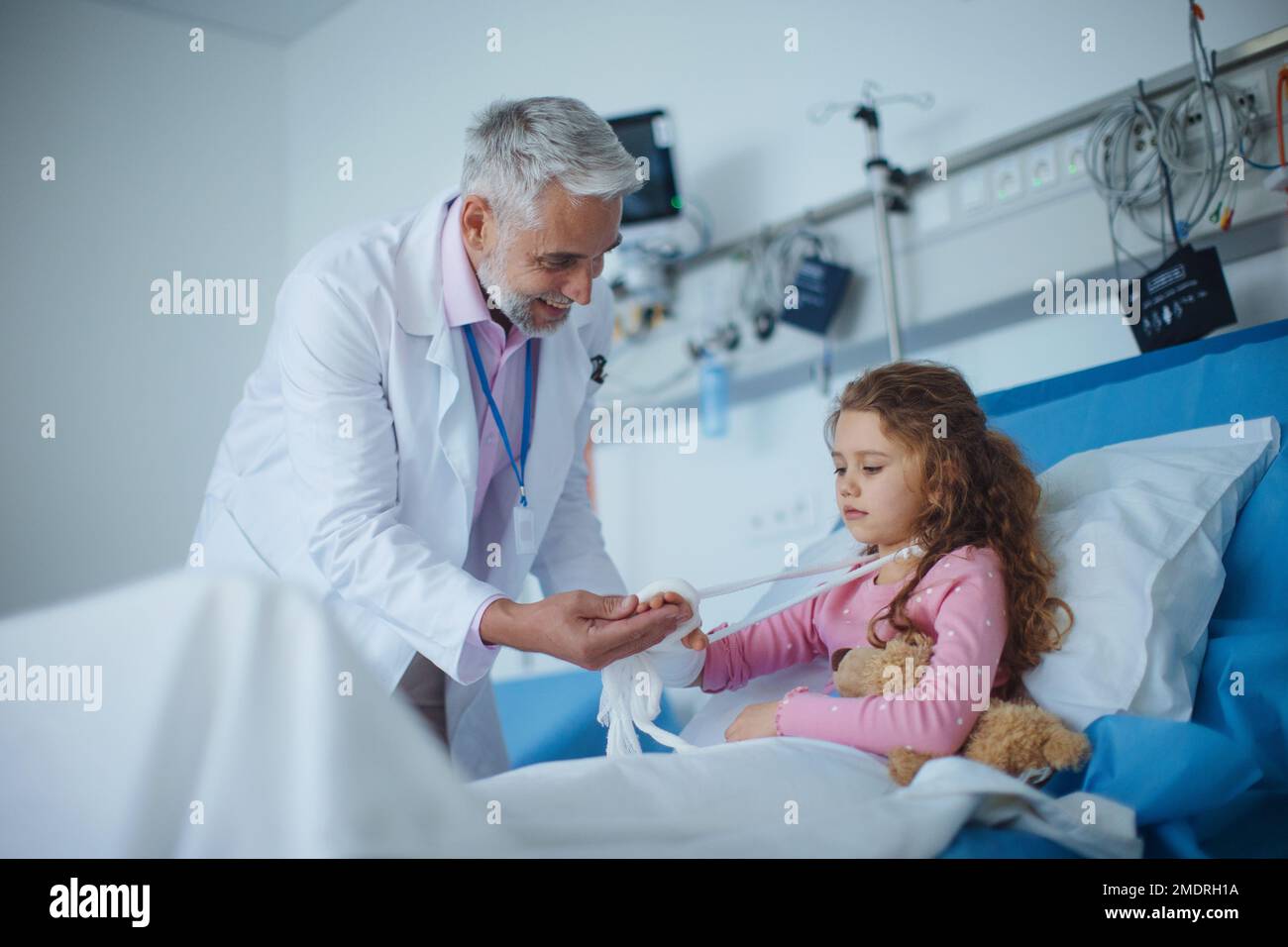 Doctor examining little girl with broken arm Stock Photo - Alamy
