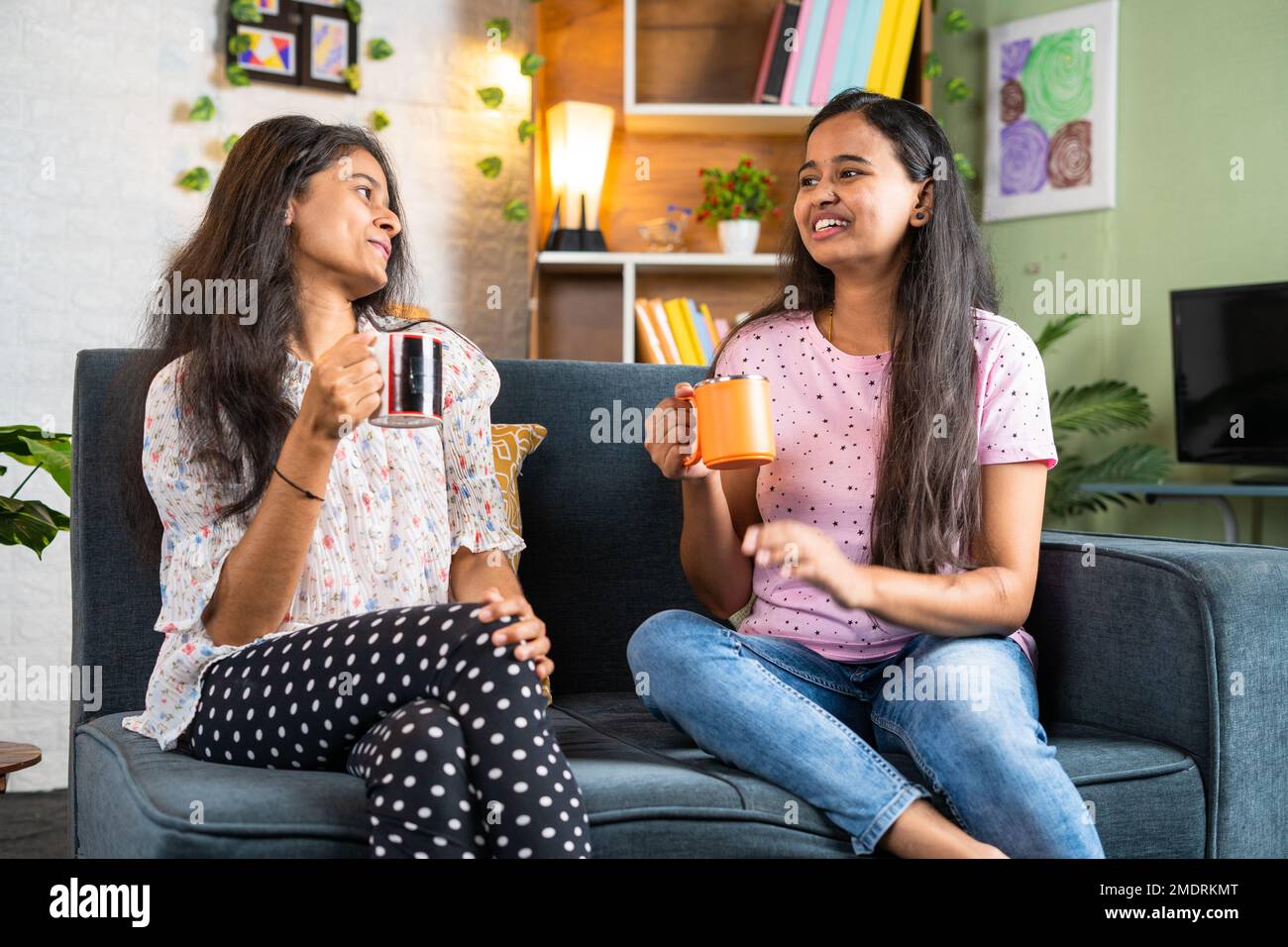 Happy smiling siblings talking eachother by drinking tea or coffee at ...