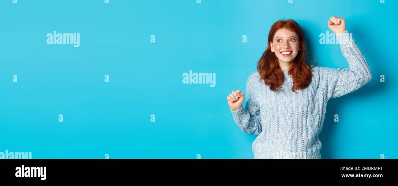 Happy redhead girl rooting for team, cheering with raised hand and ...