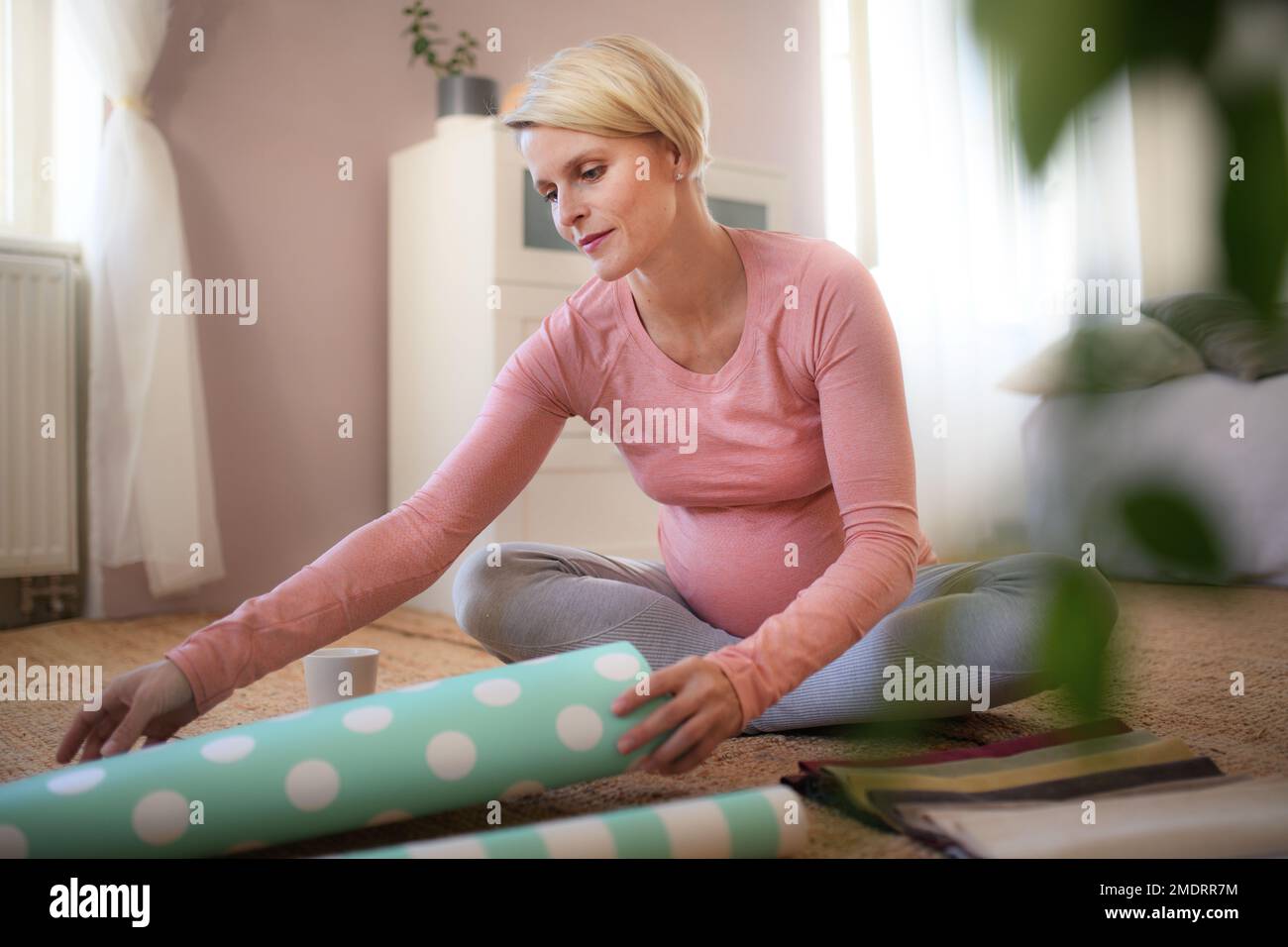 Happy pregnant woman choosing fabrics and wallpapers to child's room ...