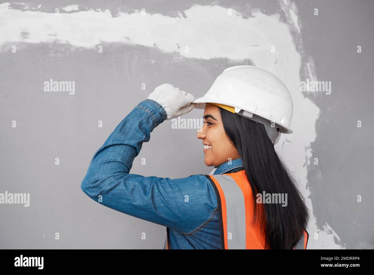 Portrait of a female South Asian construction worker tipping her hat ...