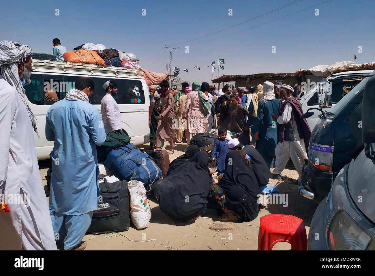Afghan families wait for transport after entering Pakistan through a ...