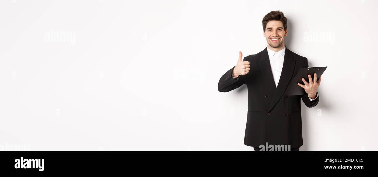 Portrait of confident businessman in black suit, holding clipboard with ...