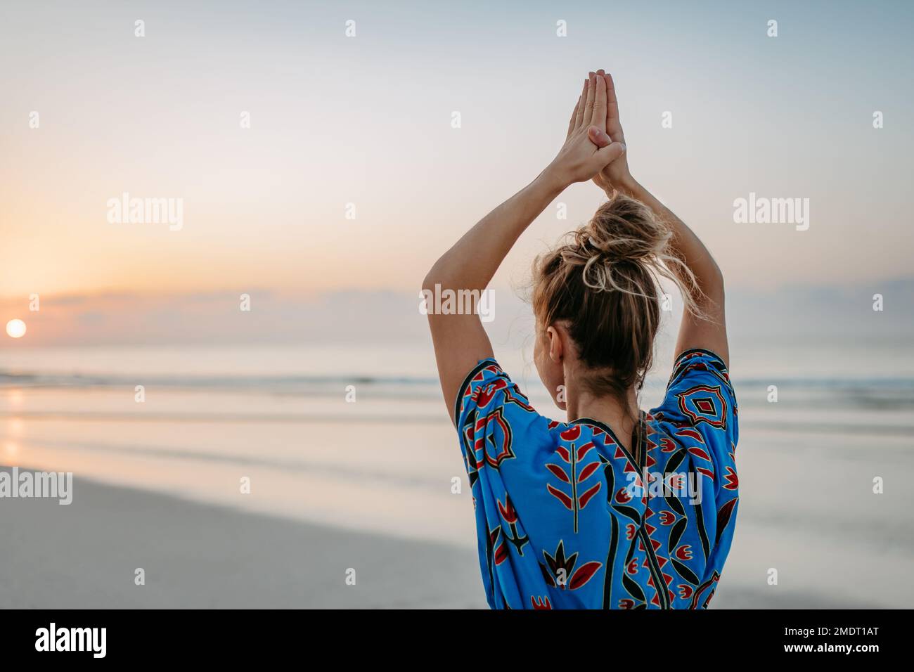 Rear view of young woman doing yoga, morning routine and healthy ...