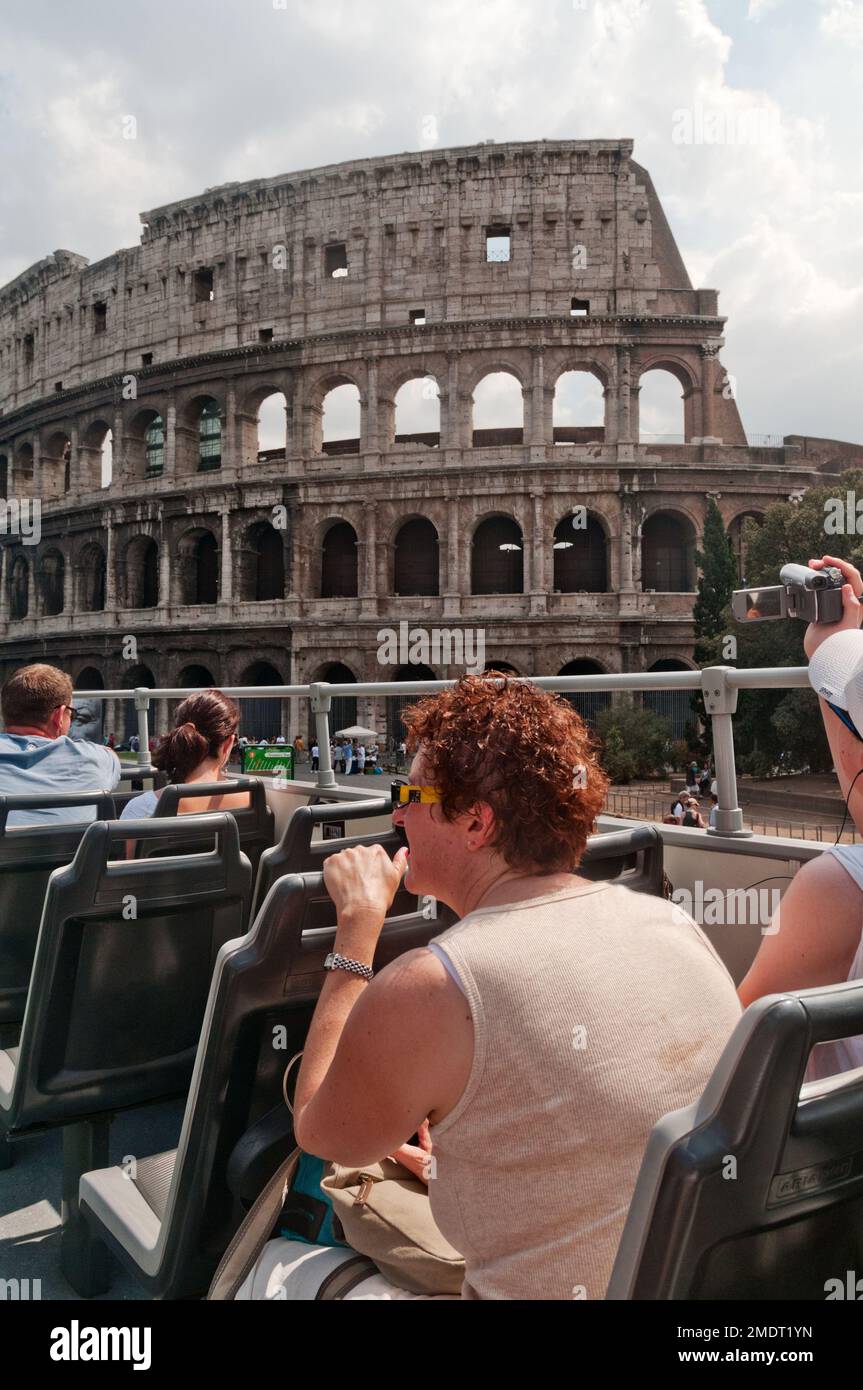 Tourists in open topped sight seeing bus passing the Colosseum, Rome ...