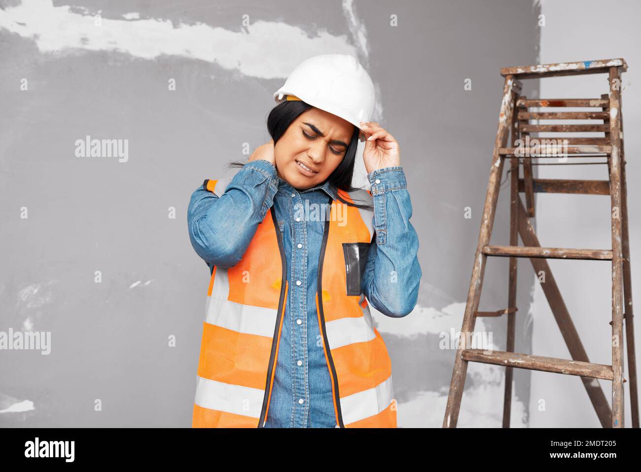 A young Indian construction worker holds her neck in pain from ...