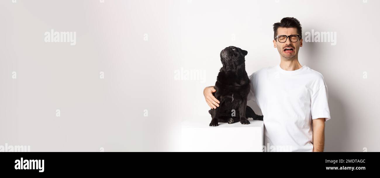 Image of sad crying man hugging his cute black pug, dog looking curious ...