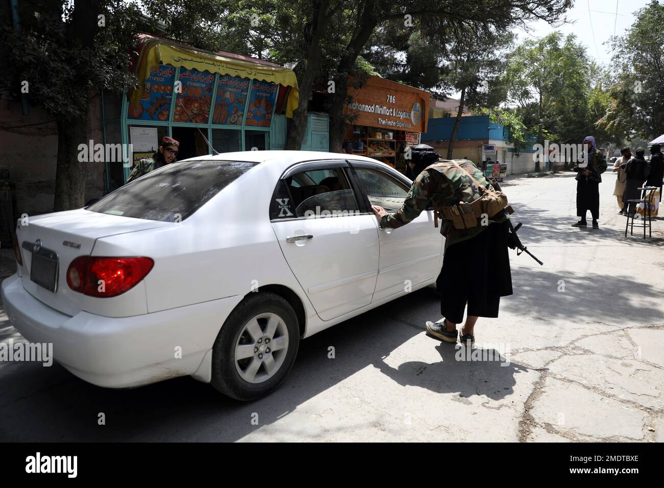 Taliban fighters search a vehicle at a checkpoint on the road in the ...