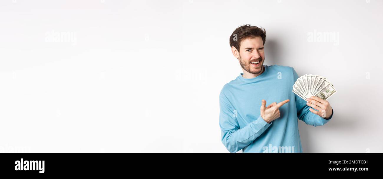 Handsome rich guy winking at camera, showing income, pointing finger at ...
