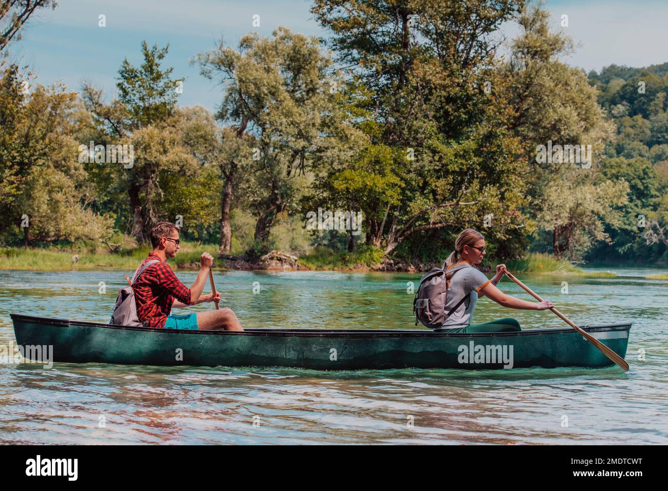 Couple adventurous explorer friends are canoeing in a wild river ...
