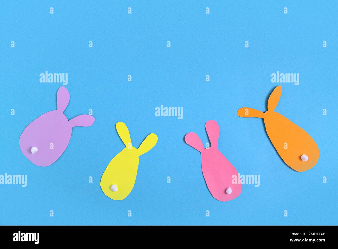 Easter bunny cut out of colored paper. Layout on blue background. The ...