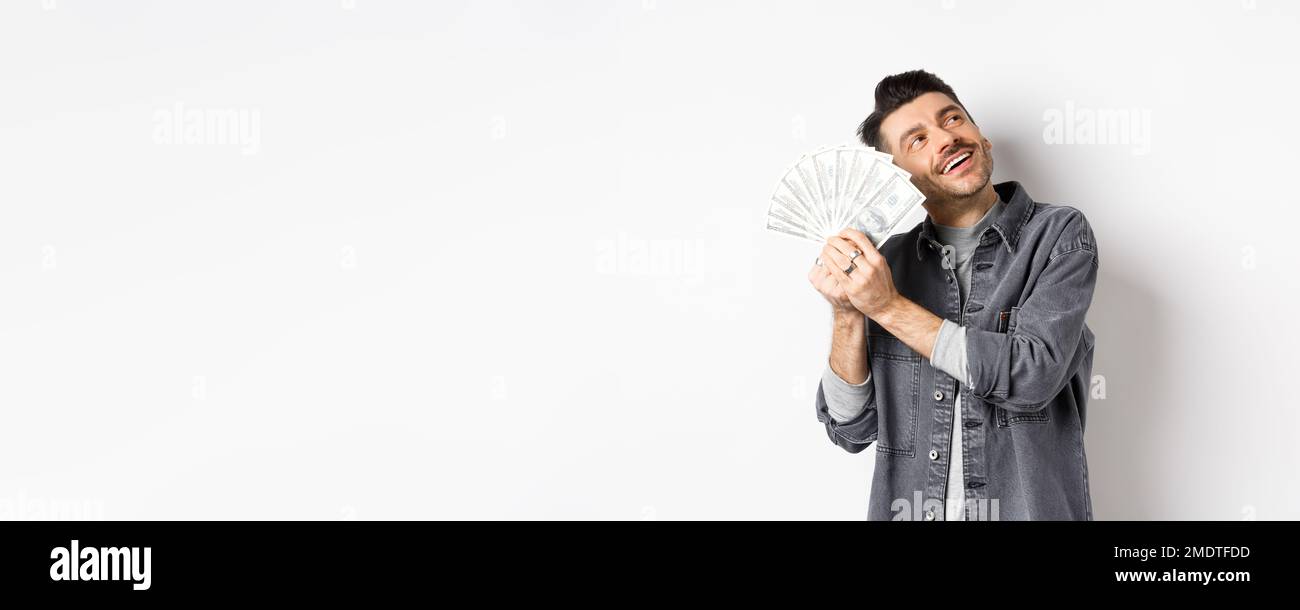Happy rich guy hugging dollar bills and daydreaming, thinking of ...