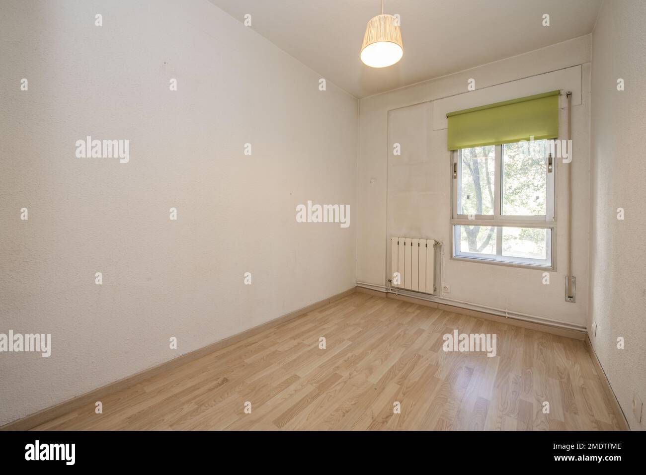 Small empty room with laminated flooring, aluminum window with green ...