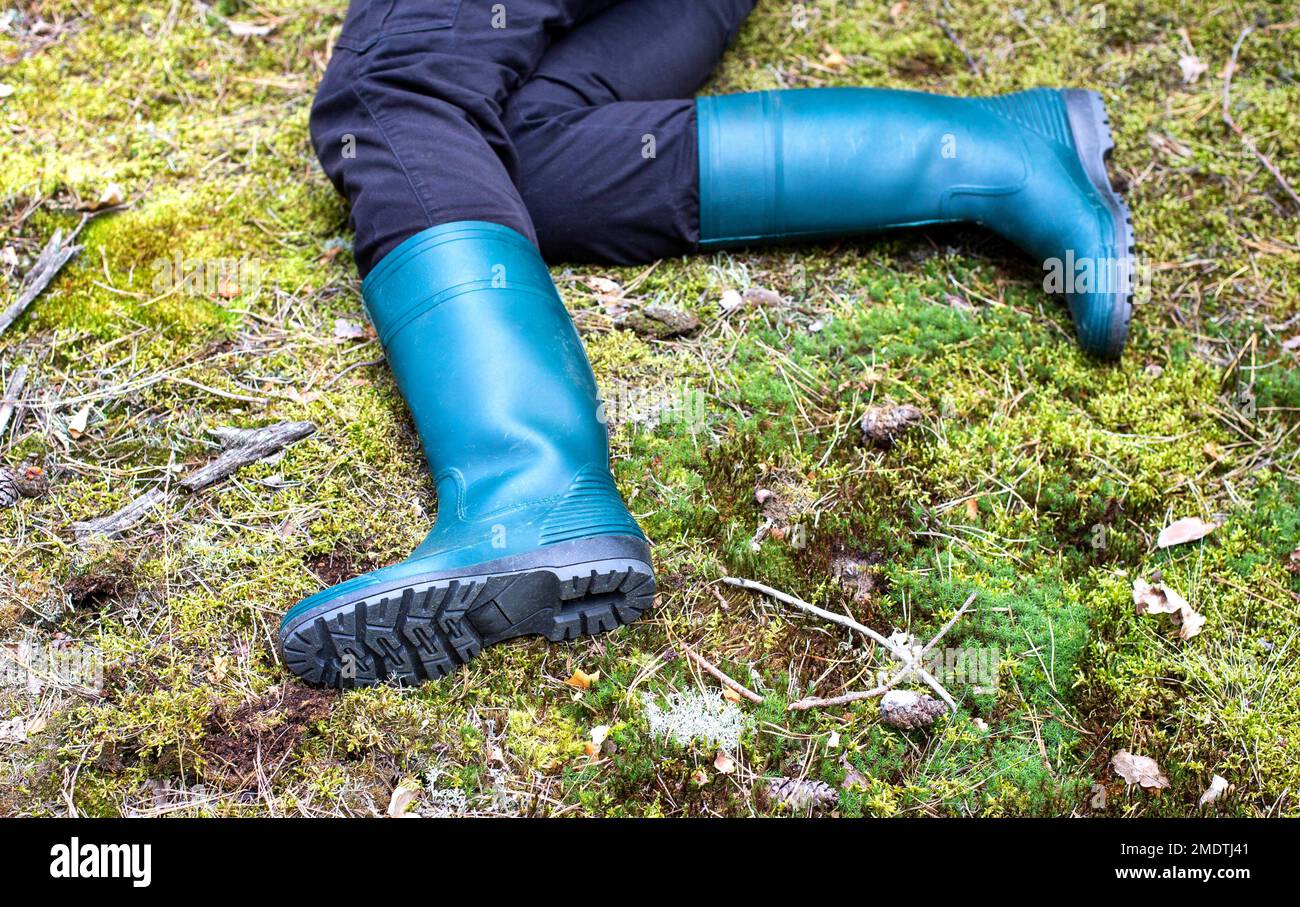 A man in boots lies in the forest on the grass. The concept of a lost ...