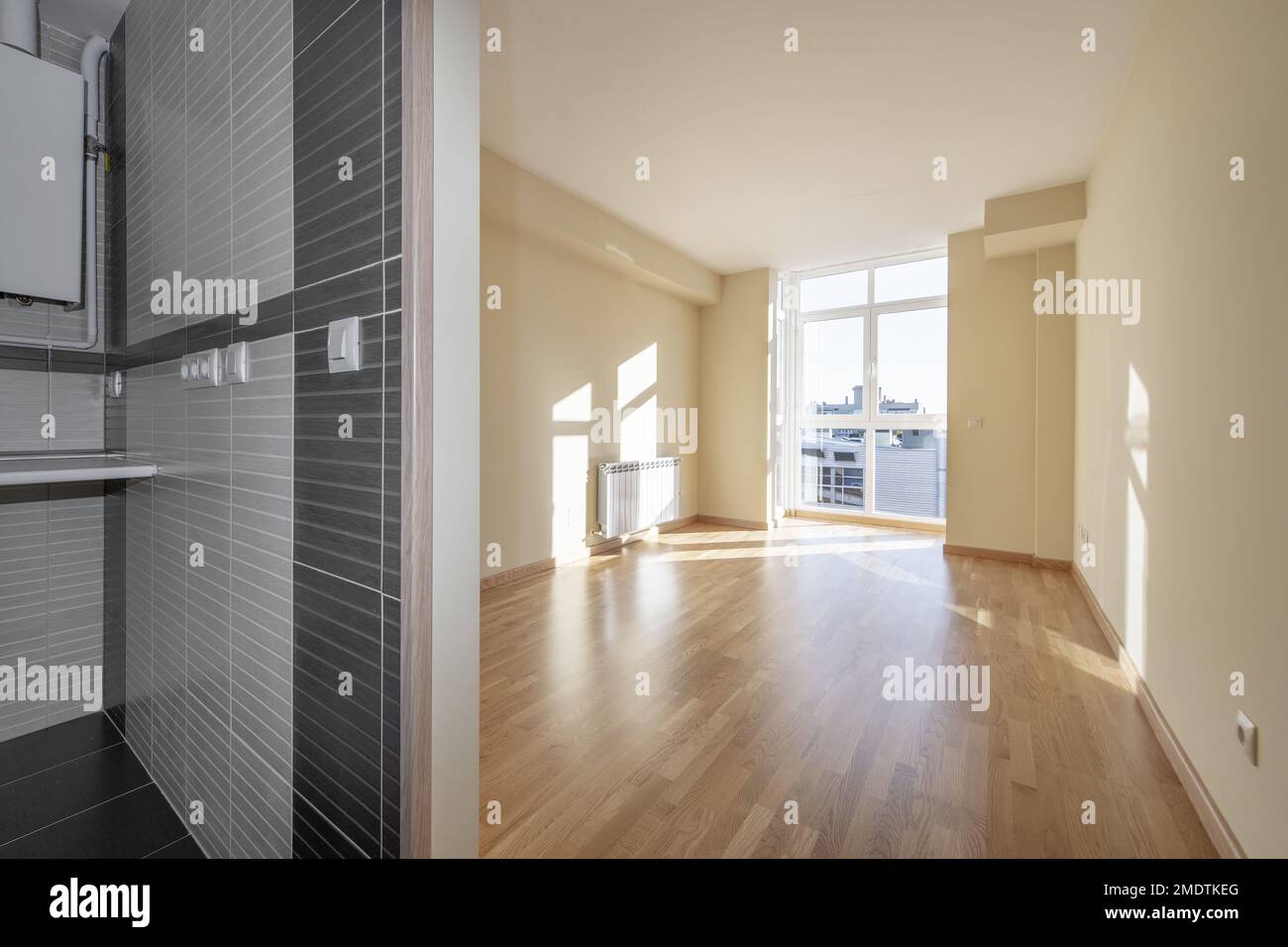 Empty room with light oak hardwood floors in a home with a kitchen ...