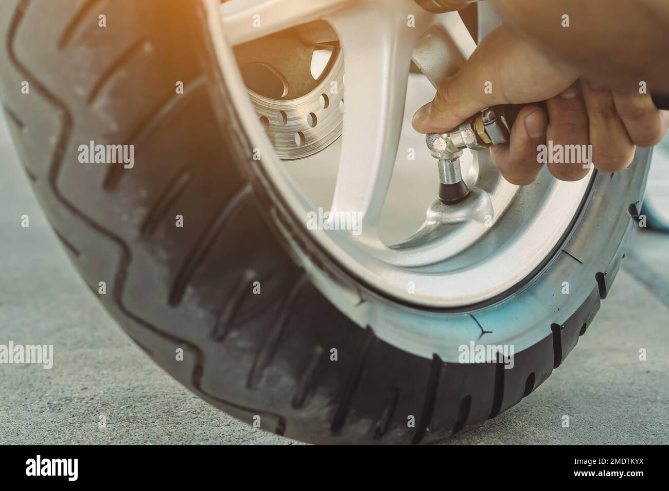 Hands of man check inflator pressure and inflates a tire on motorcycle ...