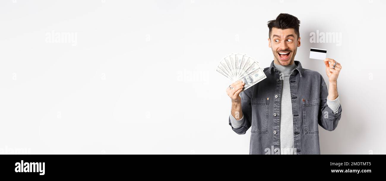 Excited guy holding plastic credit card and dollar bills, standing ...