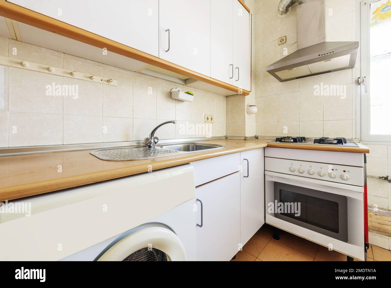 Corner small kitchen with white cabinets with wood-colored countertops ...
