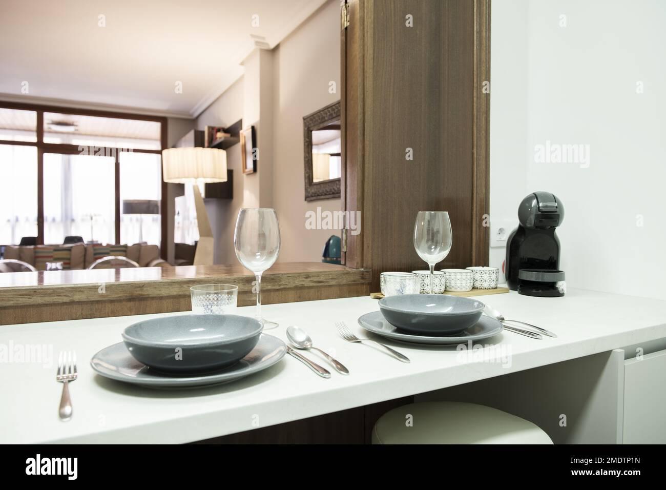 Corner of a small kitchen with white furniture and serving hatch to the ...