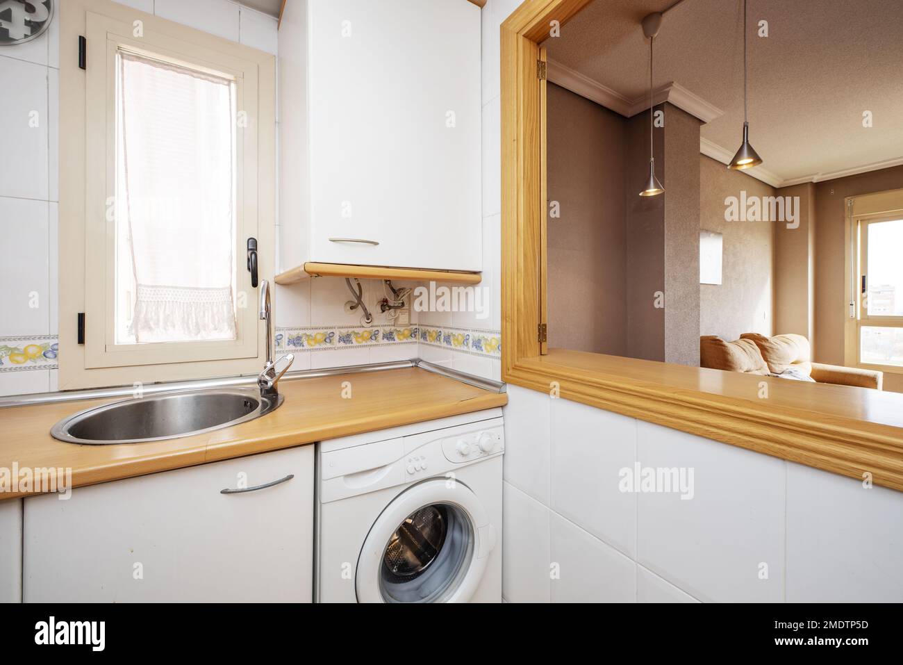 Corner of a small kitchen with white cabinets and light wooden ...