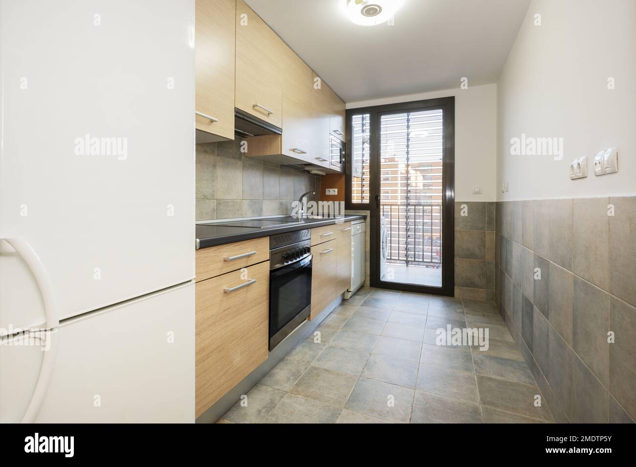 Elongated kitchen with wooden furniture with black countertop, gray ...