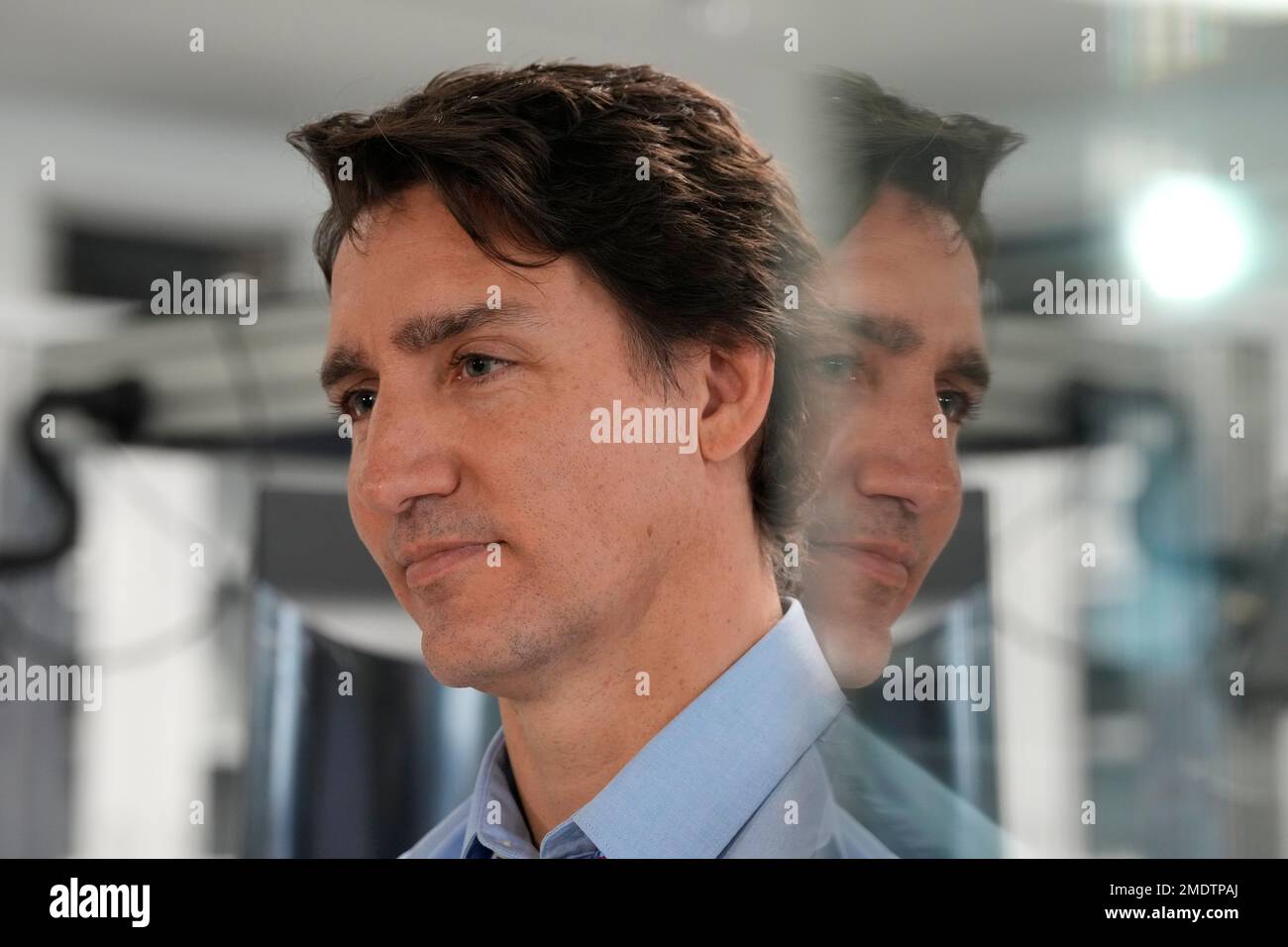 Prime Minister Justin Trudeau is reflected in a glass door as he ...