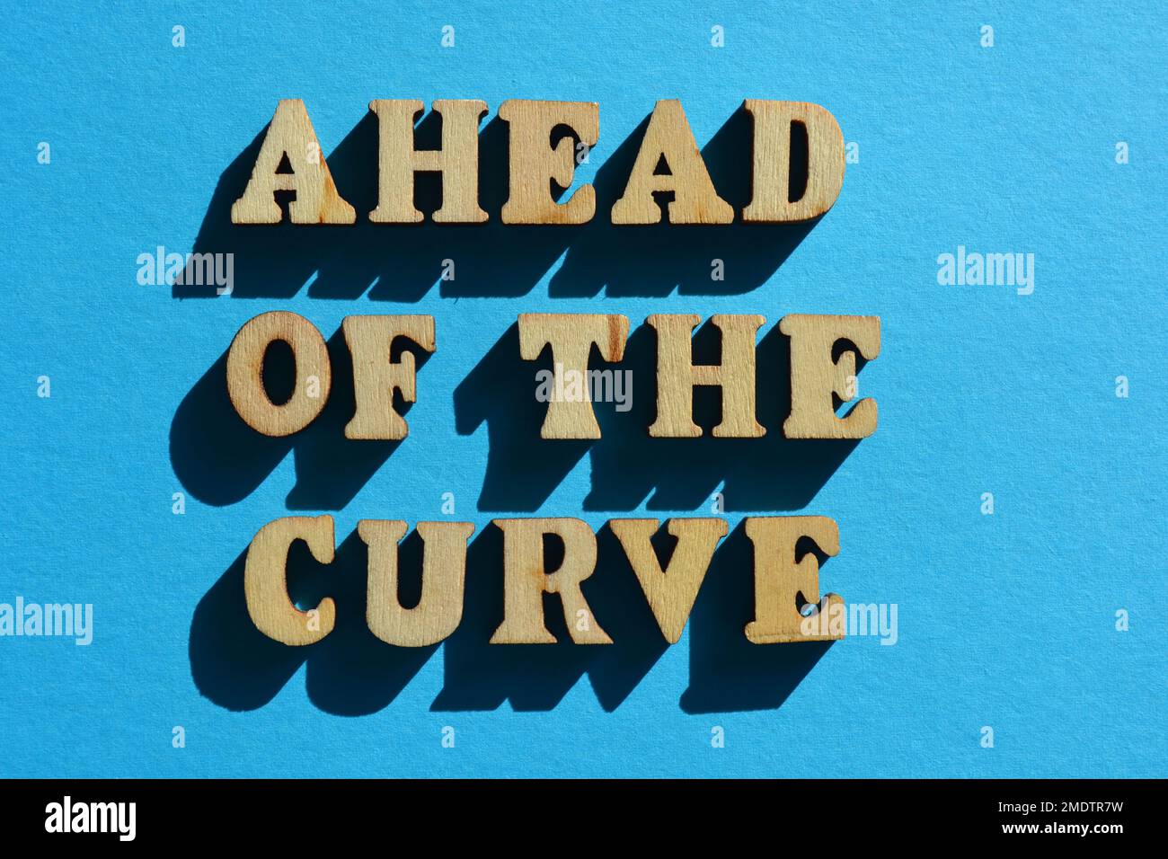 Ahead of the Curve, words in wooden alphabet letters isolated on blue ...