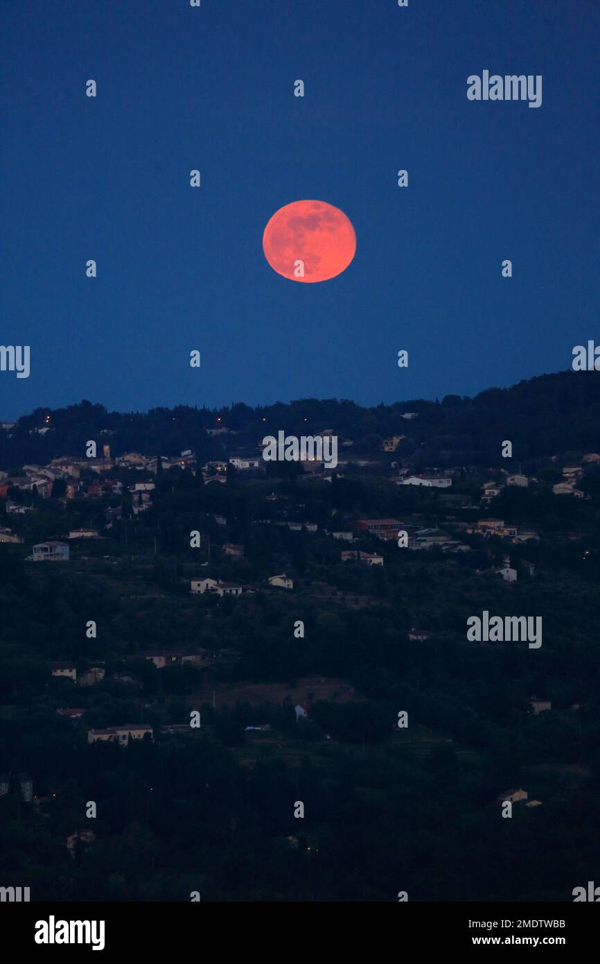 Red full moon above the village of Plascassier, Alpes Maritimes, French ...