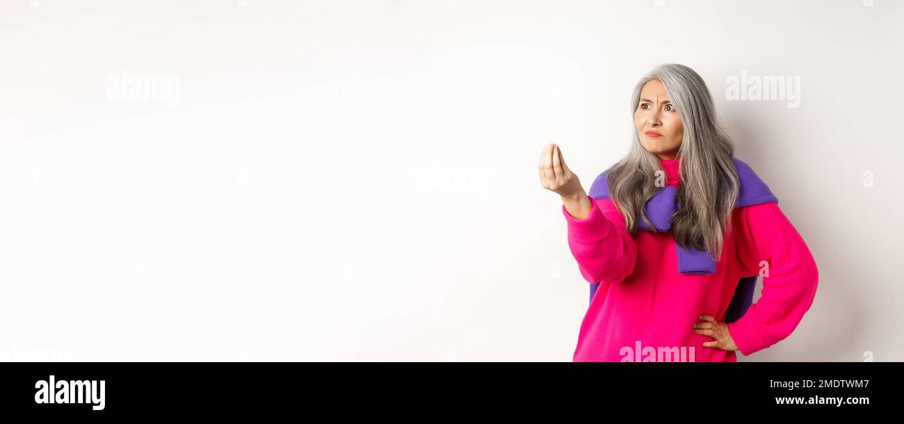 Grumpy asian grandmother complaining, showing italian what do you want ...