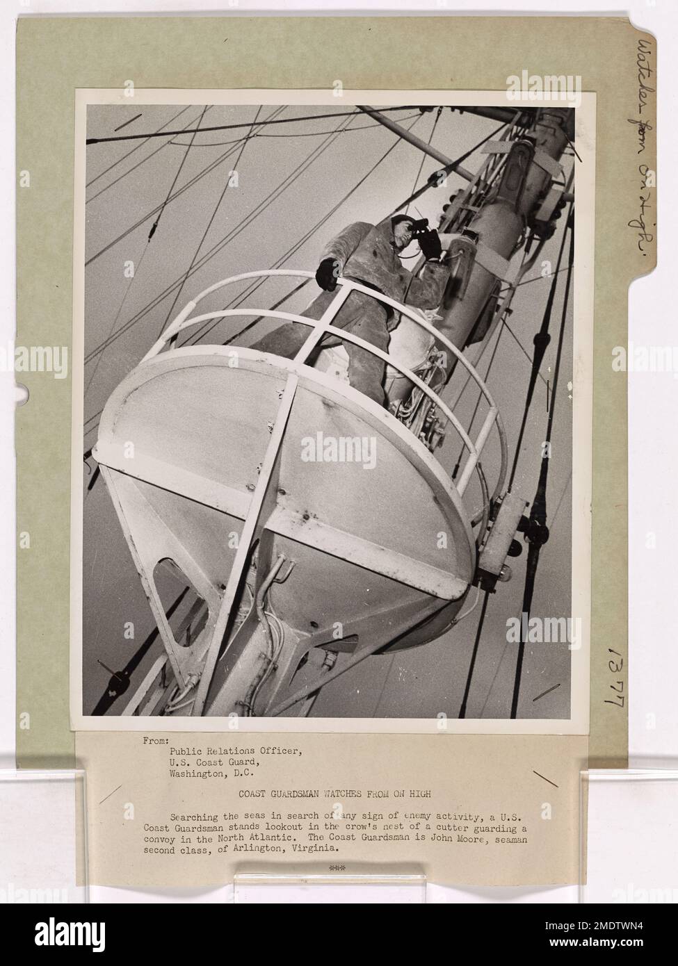 This image shows a Coast Guardsman standing lookout in the crow’s nest ...