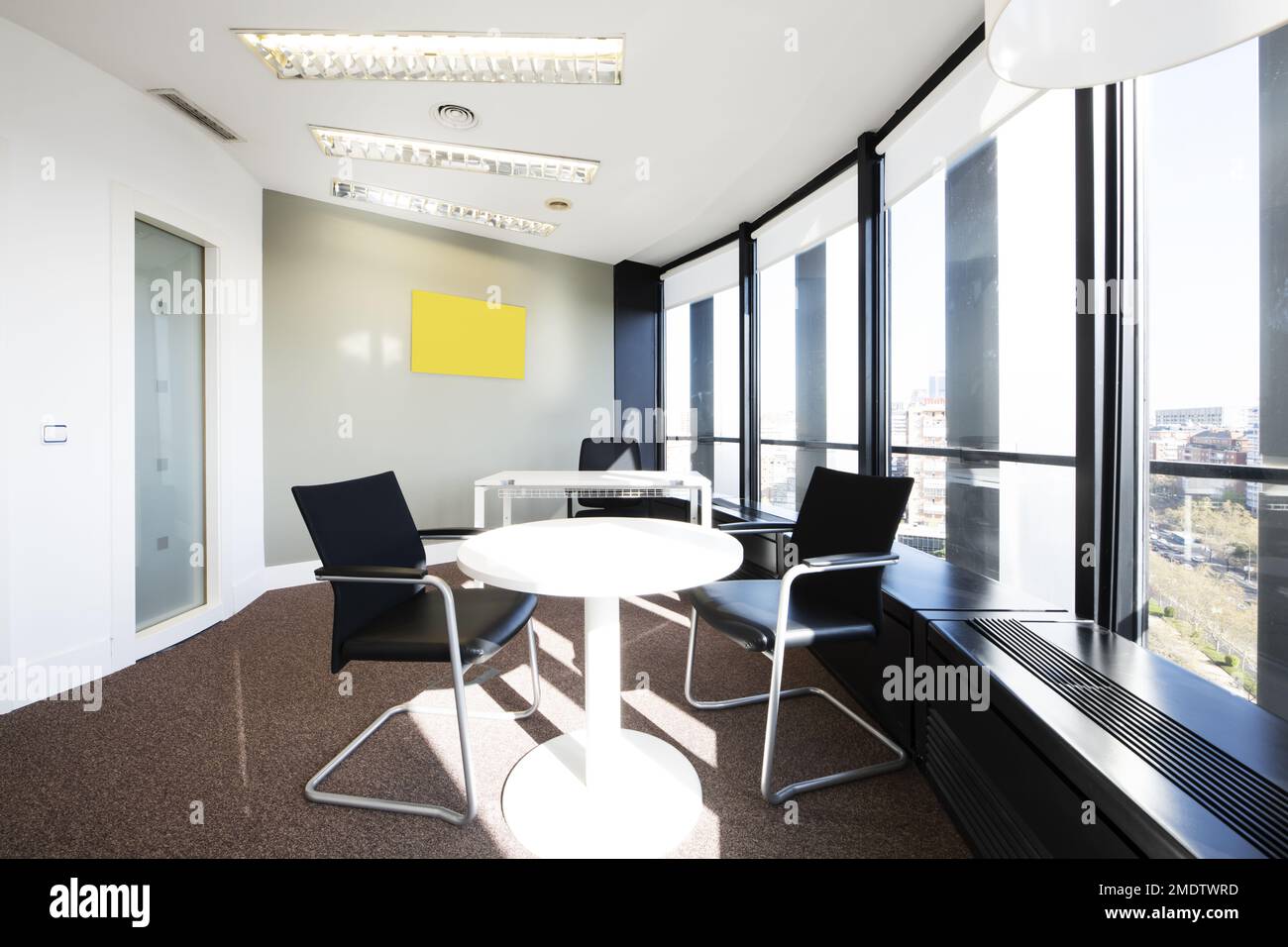 Office with a small white round table next to a large window with a ...