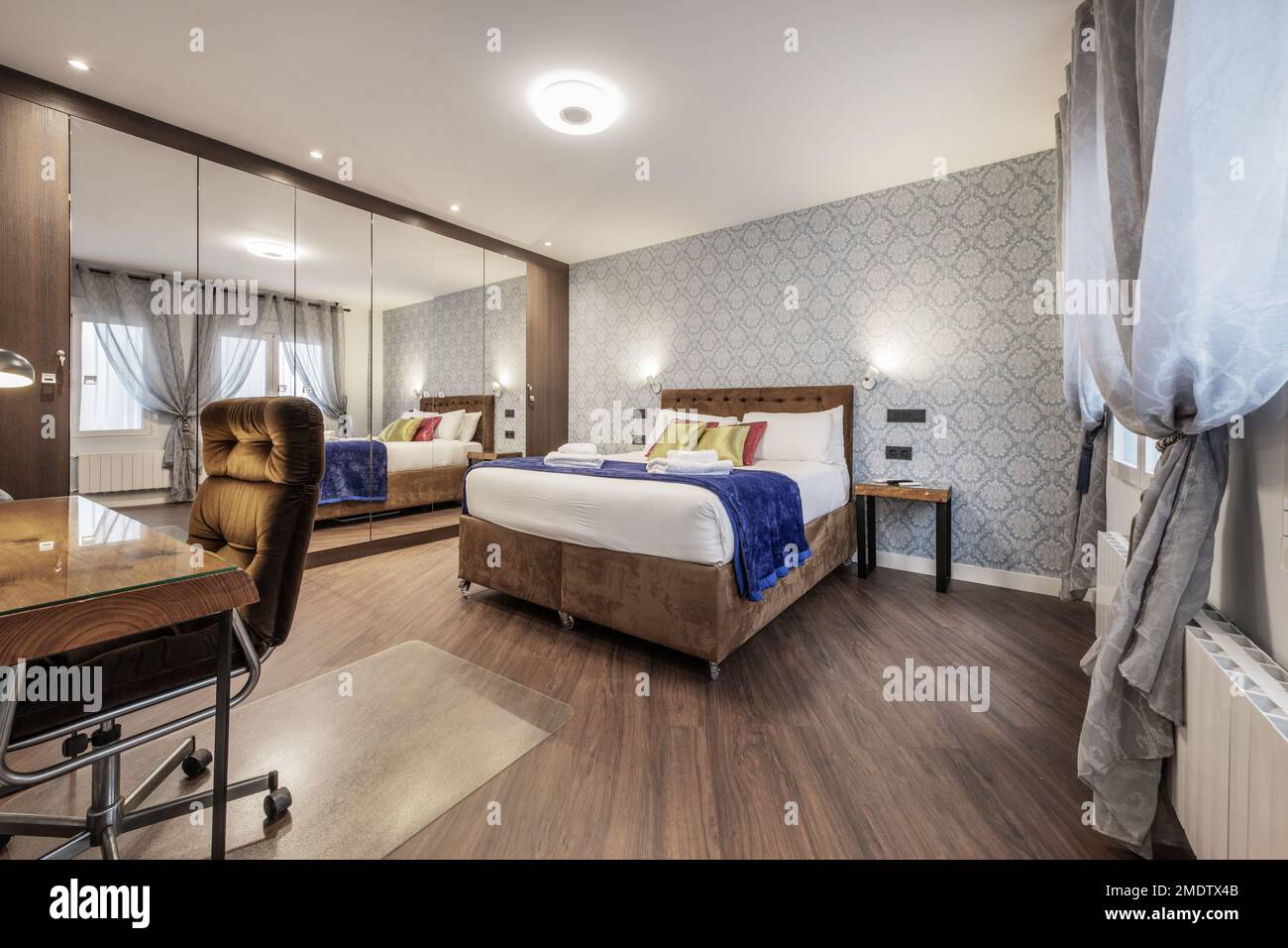 Bedroom with a wall covered by a built-in wardrobe with mirrored doors ...