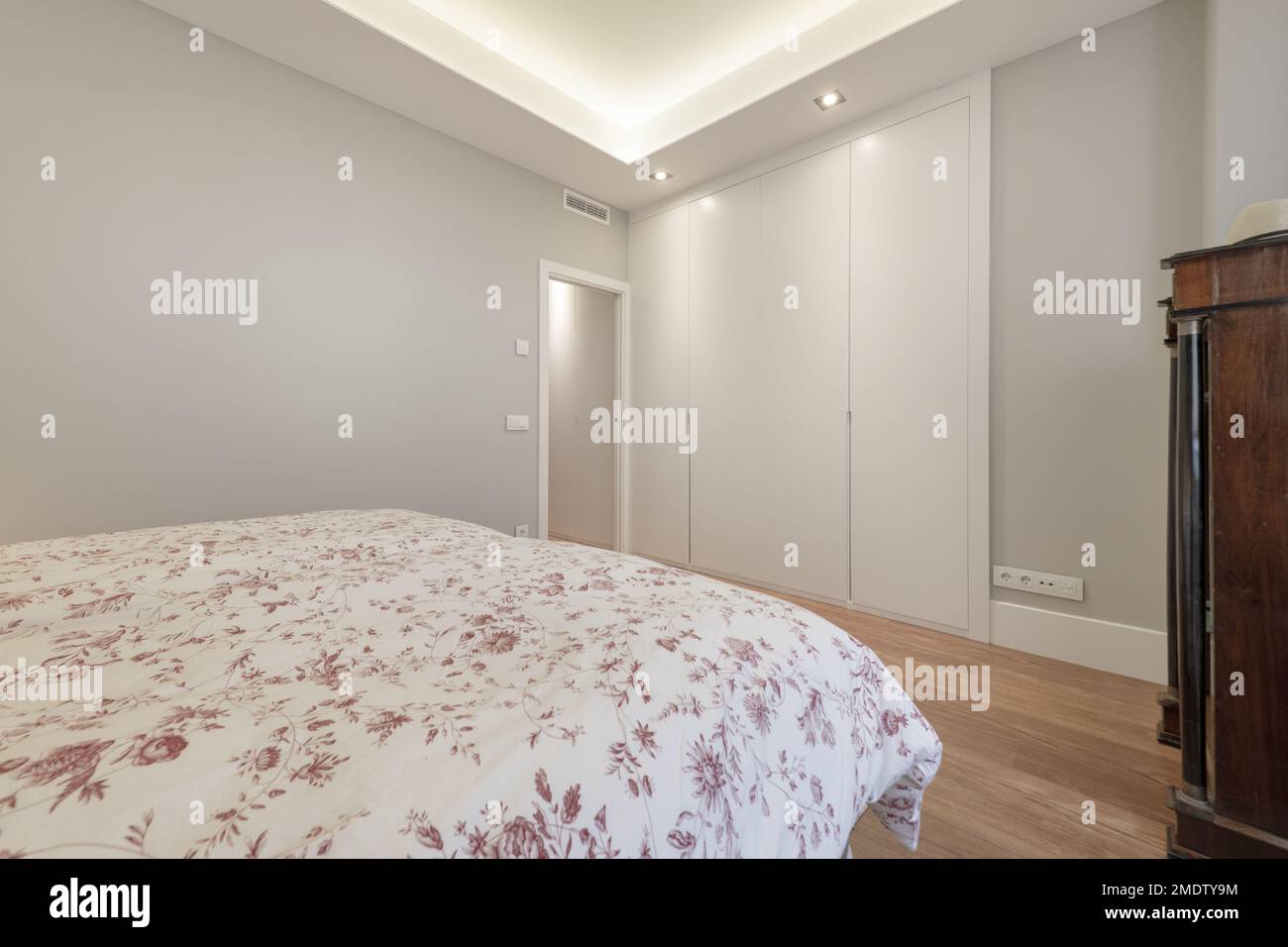 Room with a double bed with a patterned quilt, a built-in wardrobe with ...