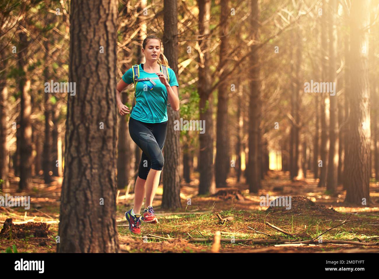 Keep challenging yourself. a young woman out running in the forest ...