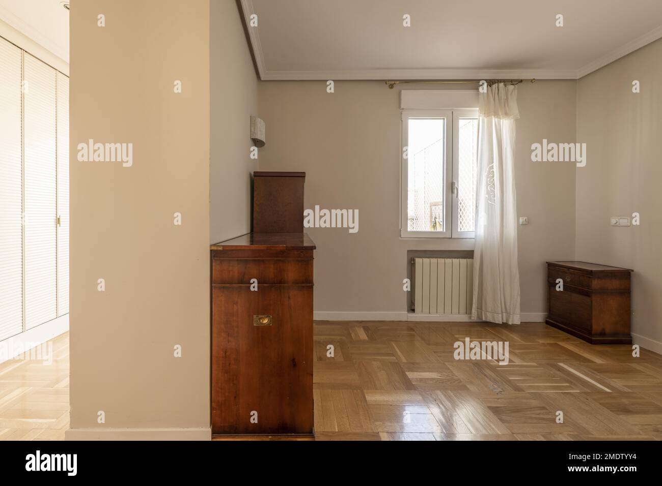 A semi-empty room with some vintage-style wooden furniture with a ...