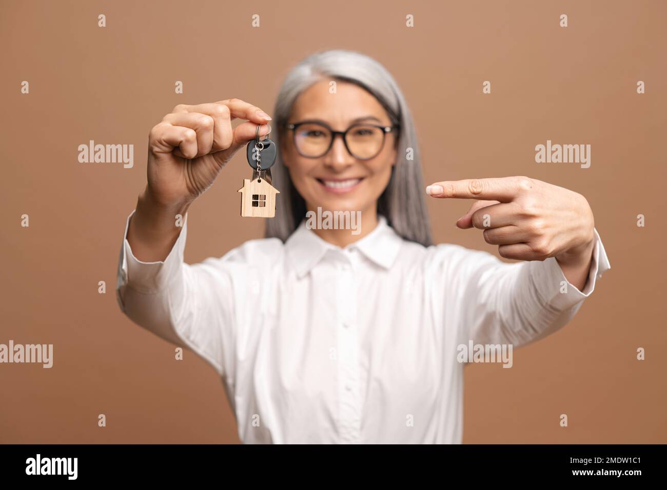 Smiling woman pointing at the keys from new property, happy buyer of ...