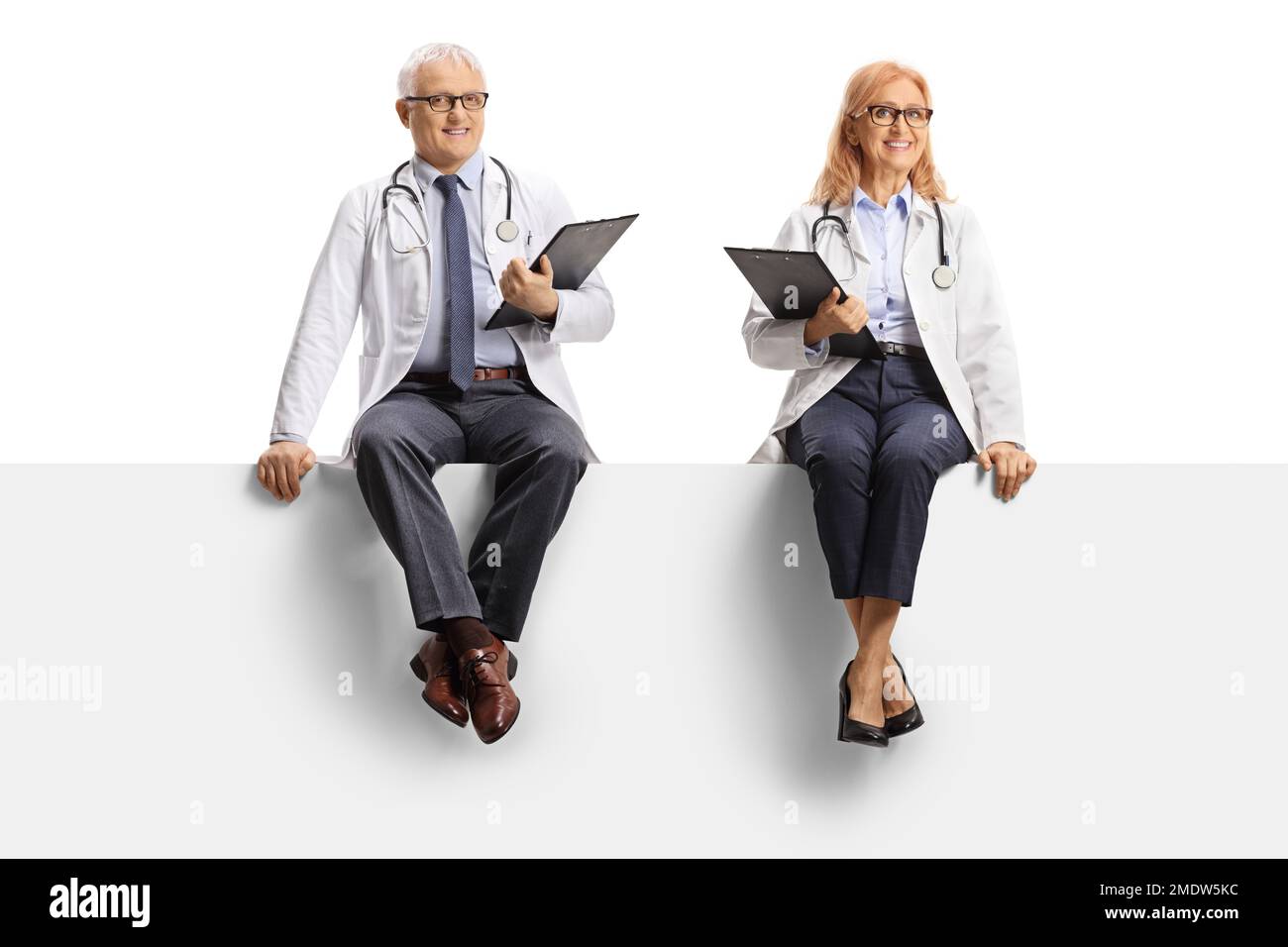 Male and female doctors sitting on a blank panel and smiling isolated ...