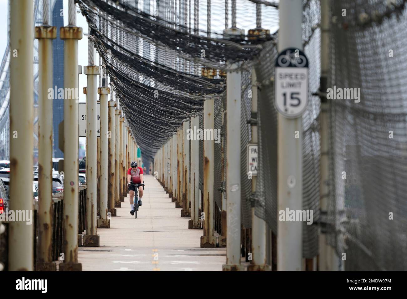 Bicyclists use the pedestrian walkway, covered with netting, on the ...