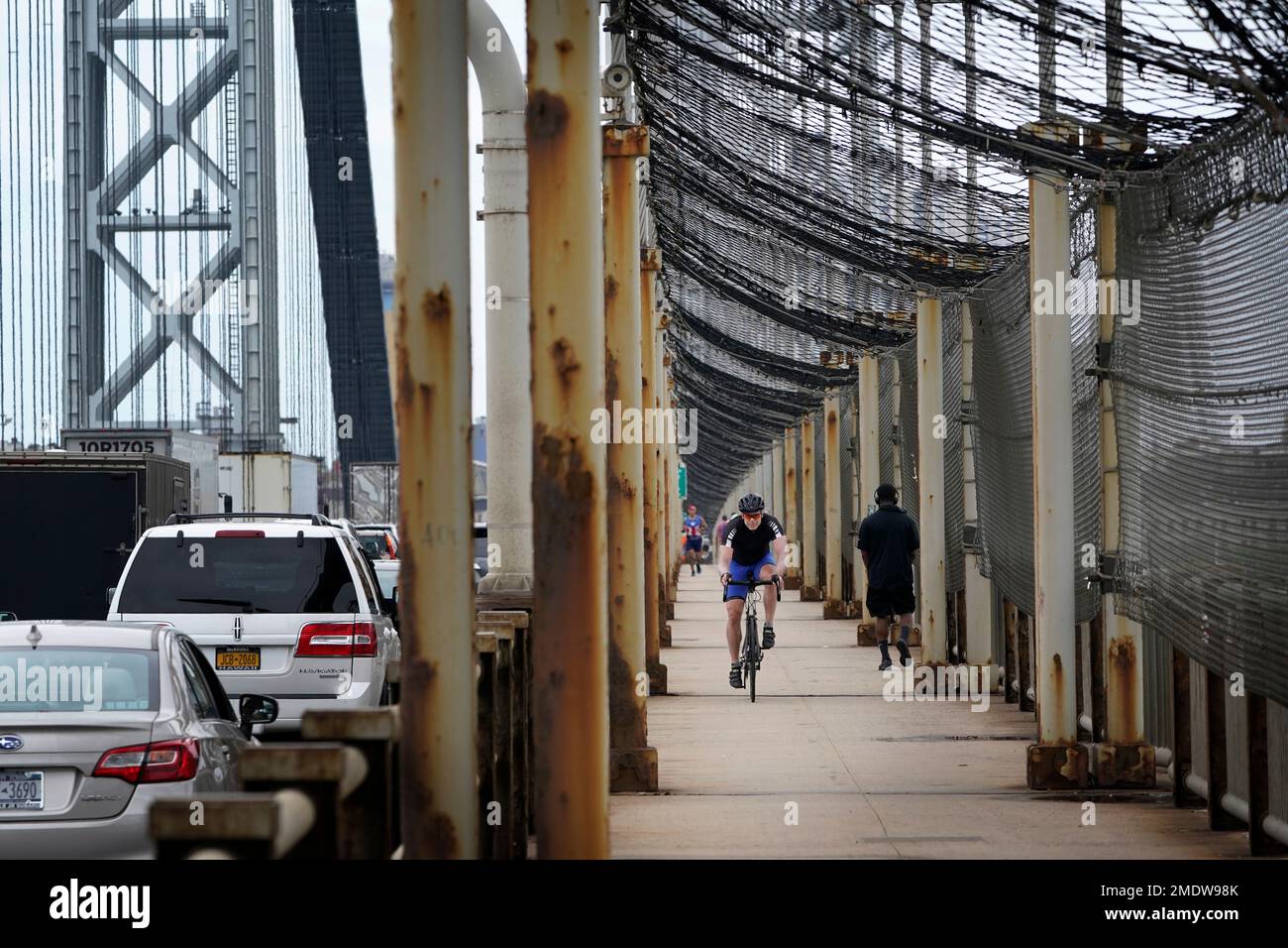 People use the pedestrian walkway, covered with netting, on the George ...