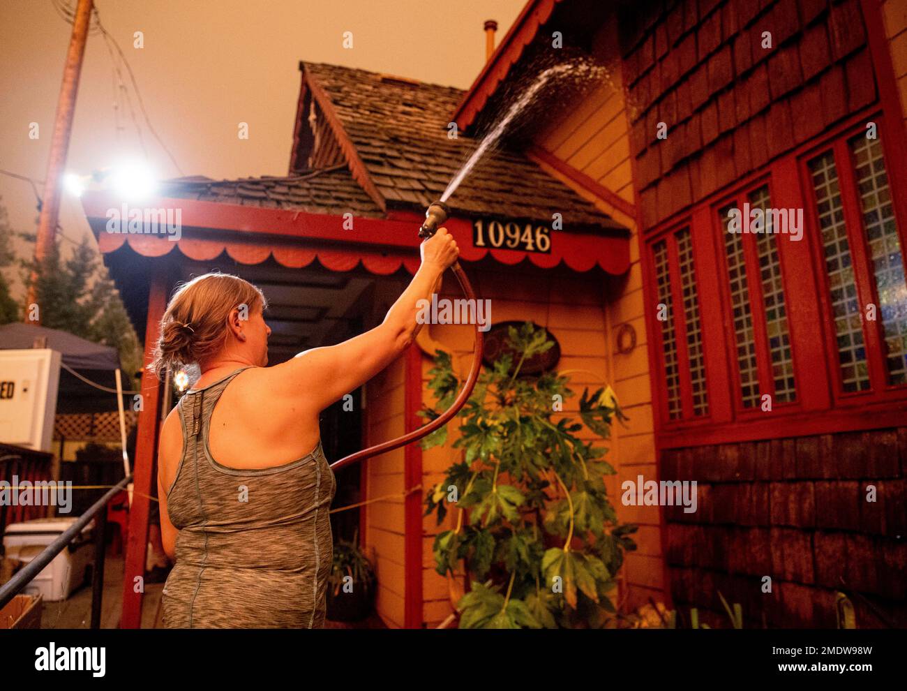 Jennifer Whitmore sprays her home with water as the Caldor fire burns ...