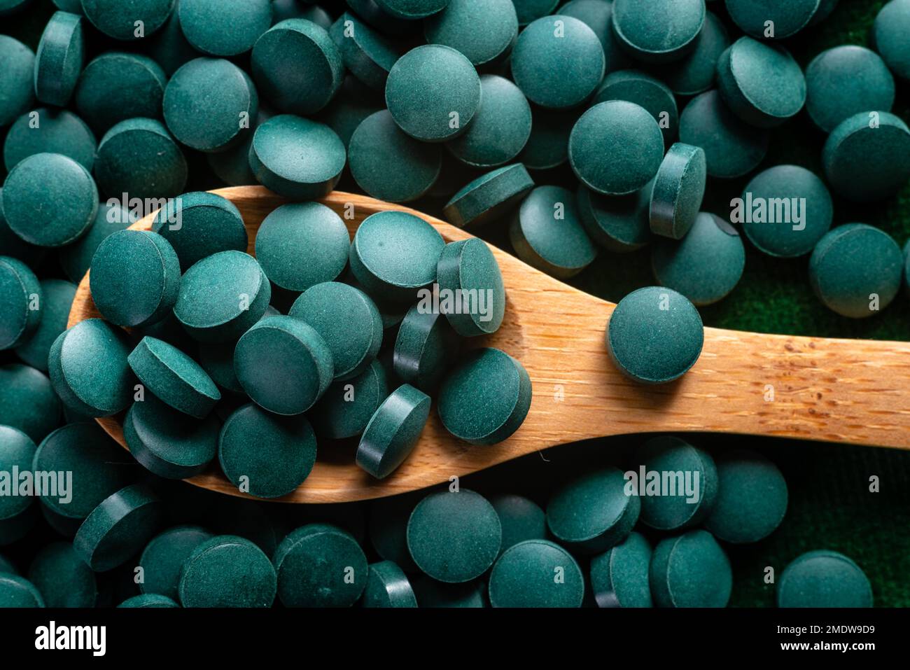 Green Organic Spirulina in algae pills tablets bamboo wood spoon rich ...