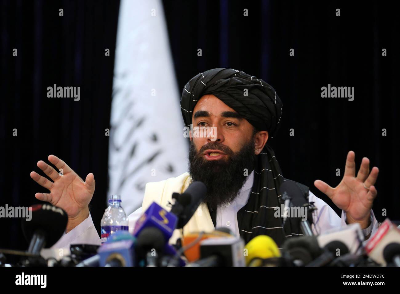 In front of a Taliban flag, Taliban spokesman Zabihullah Mujahid speaks ...