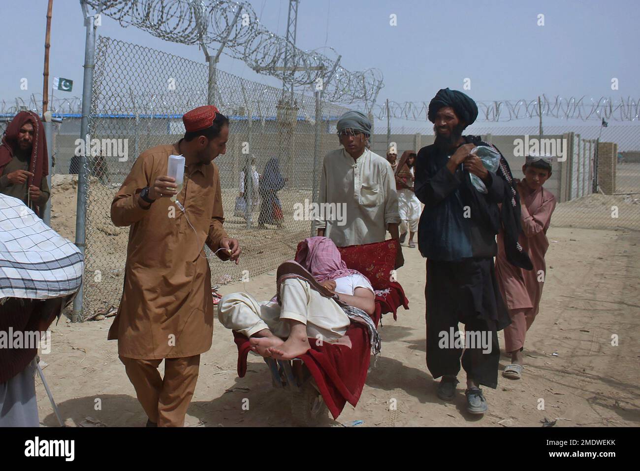 A porter pushes a wheelbarrow carrying an ill Afghan national as he and ...