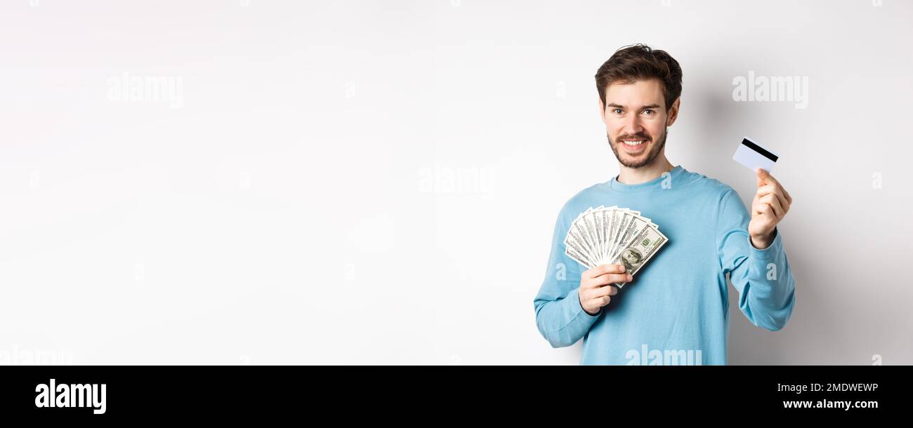 Handsome young man smiling and offering payment in cash and contactless ...