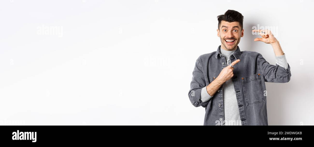Excited man showing small size, pointing finger at little thing and ...