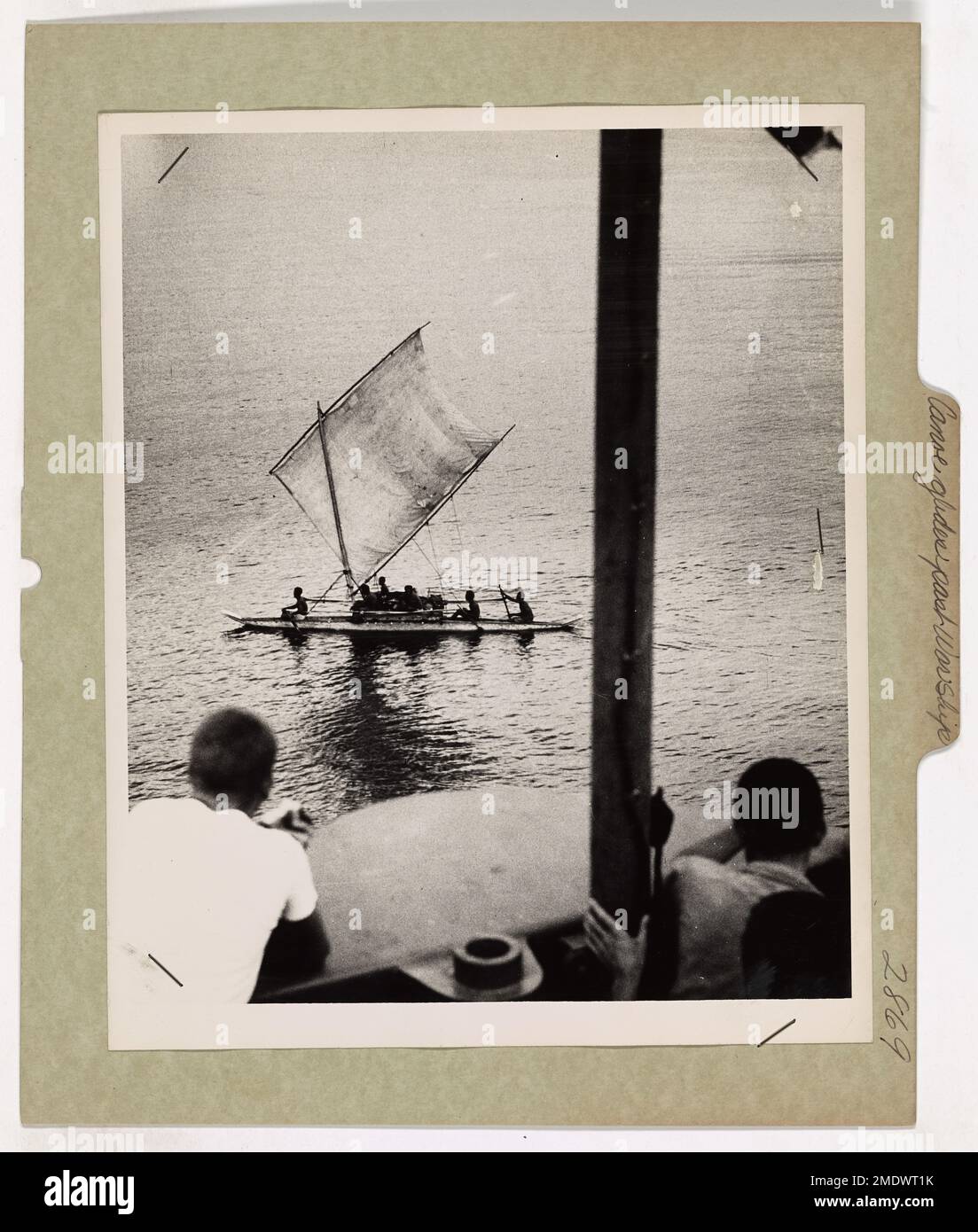 In the South Seas, a primitive canoe with a native crew glides past a ...