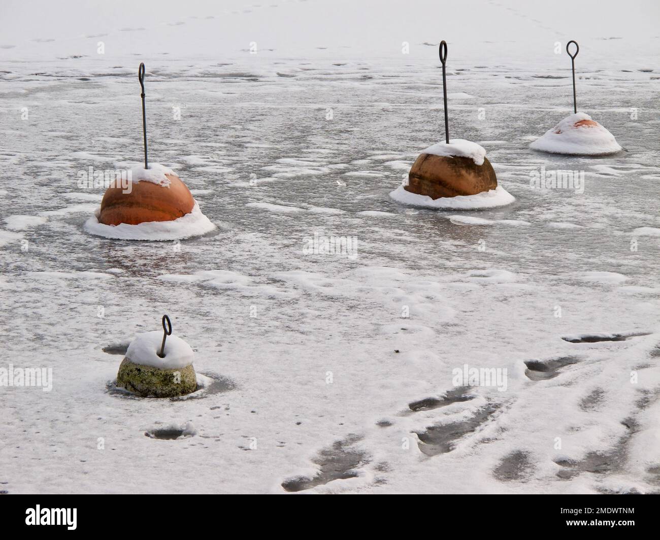 Lake with red anchor buoys frozen in the ice in winter Stock Photo - Alamy