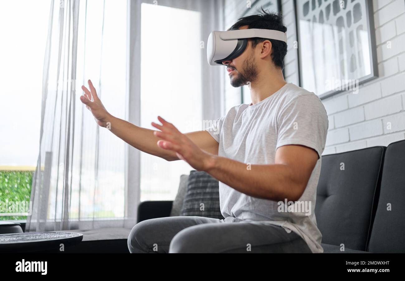 Virtual reality, hands and man on sofa with futuristic headset for ...