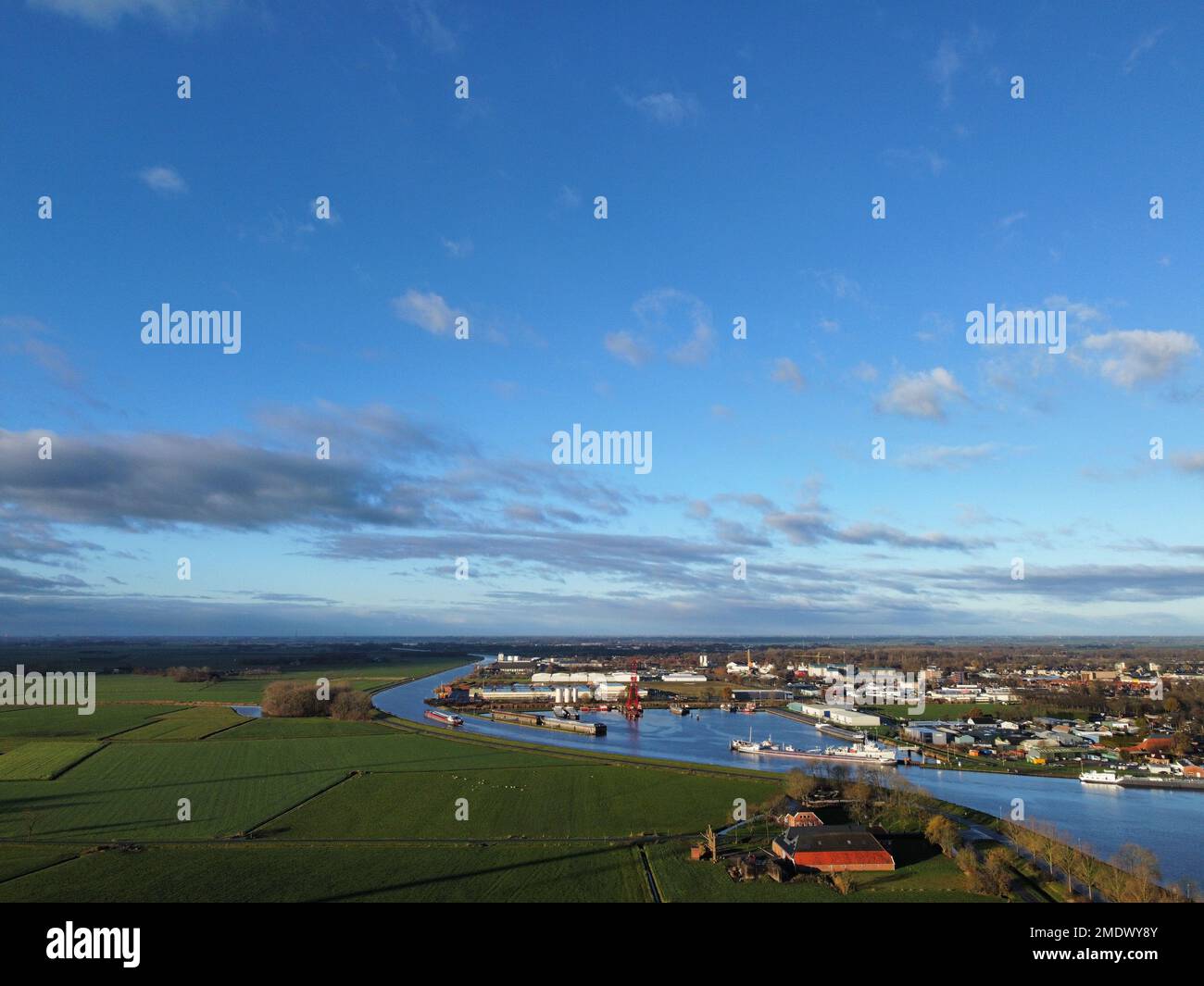 An aerial shot of a canal flowing along a small town under the blue sky ...